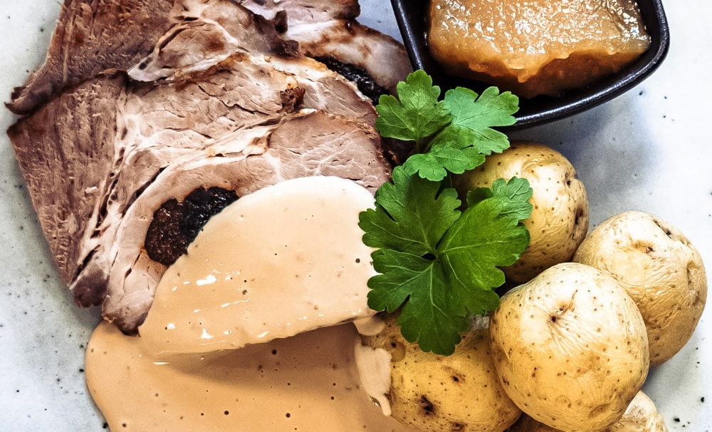 Plommonspäckad fläskkarré med kokt potatis samt gräddsås och äppelmos ...