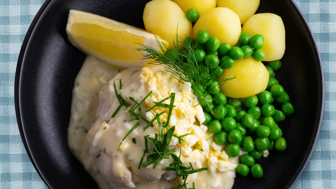 Pocherad Kolja med äggsås serveras med kokt potatis och gröna ärtor ...